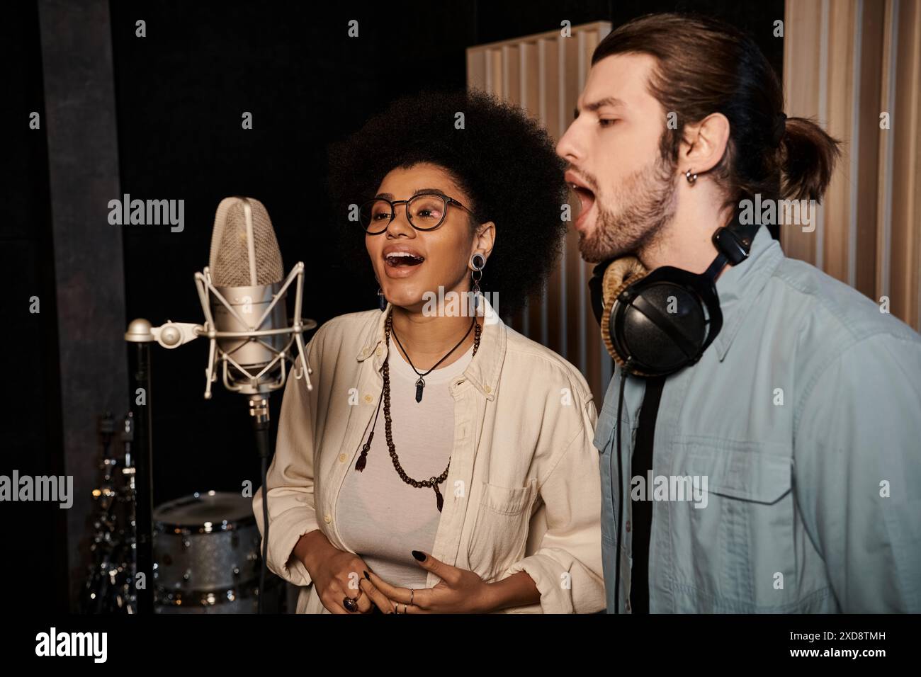A man and woman passionately sing into microphones in a recording ...