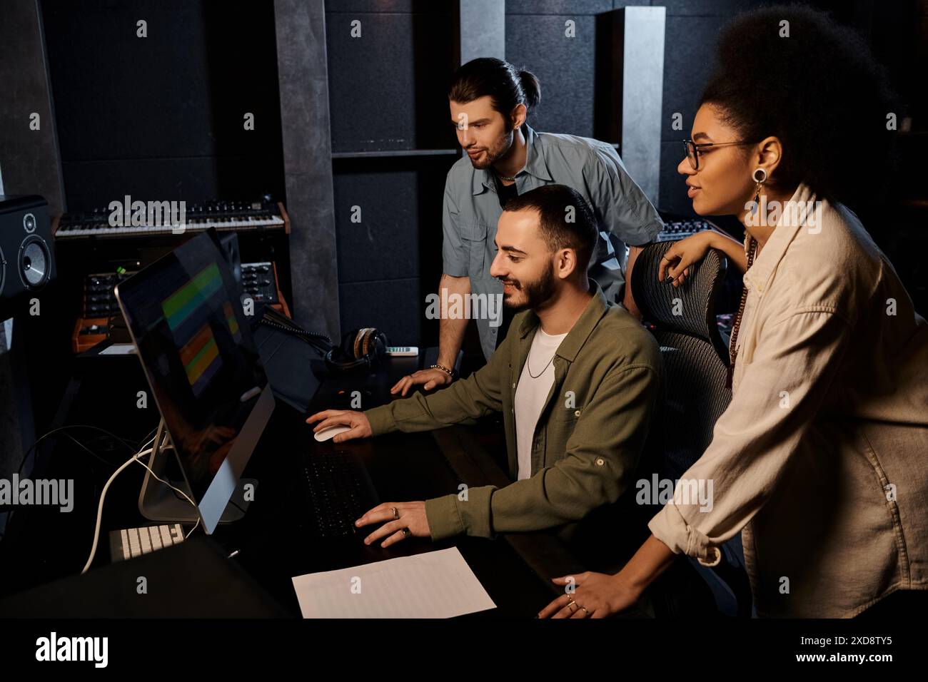 A diverse group of musicians studying a computer screen in a recording ...