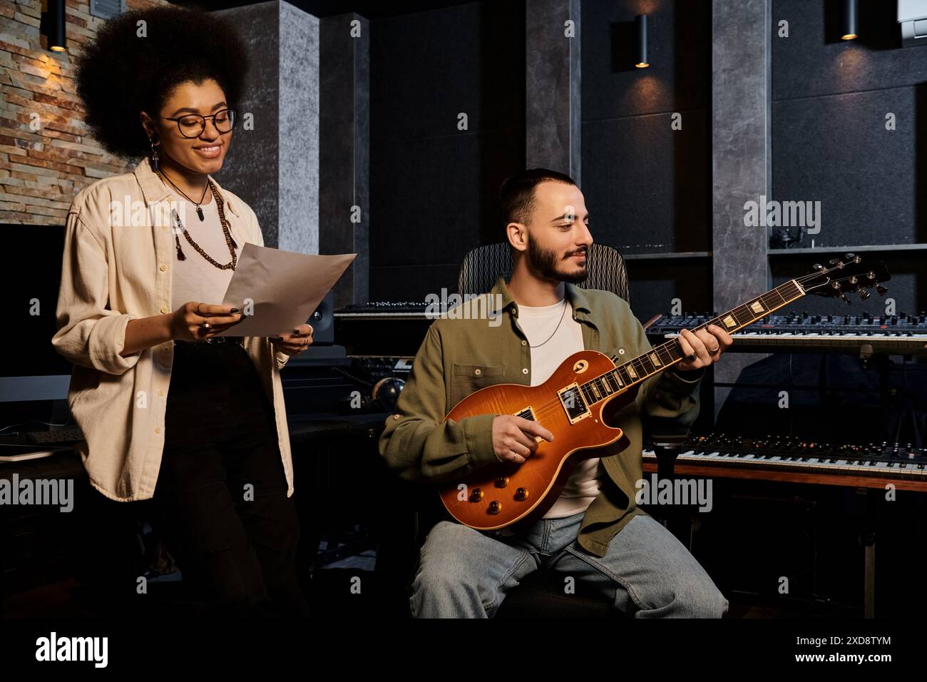 A man and woman playing guitar in a recording studio during a music ...