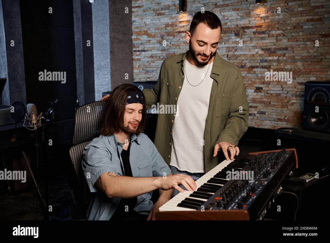 Two men in a recording studio, deeply engrossed, playing a keyboard ...