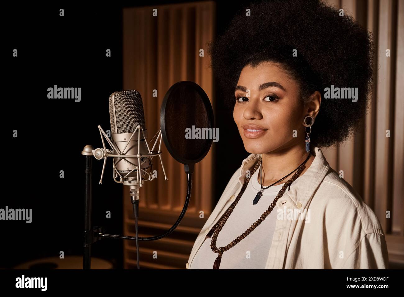 A woman with a voluminous hair stands confidently in a recording studio ...