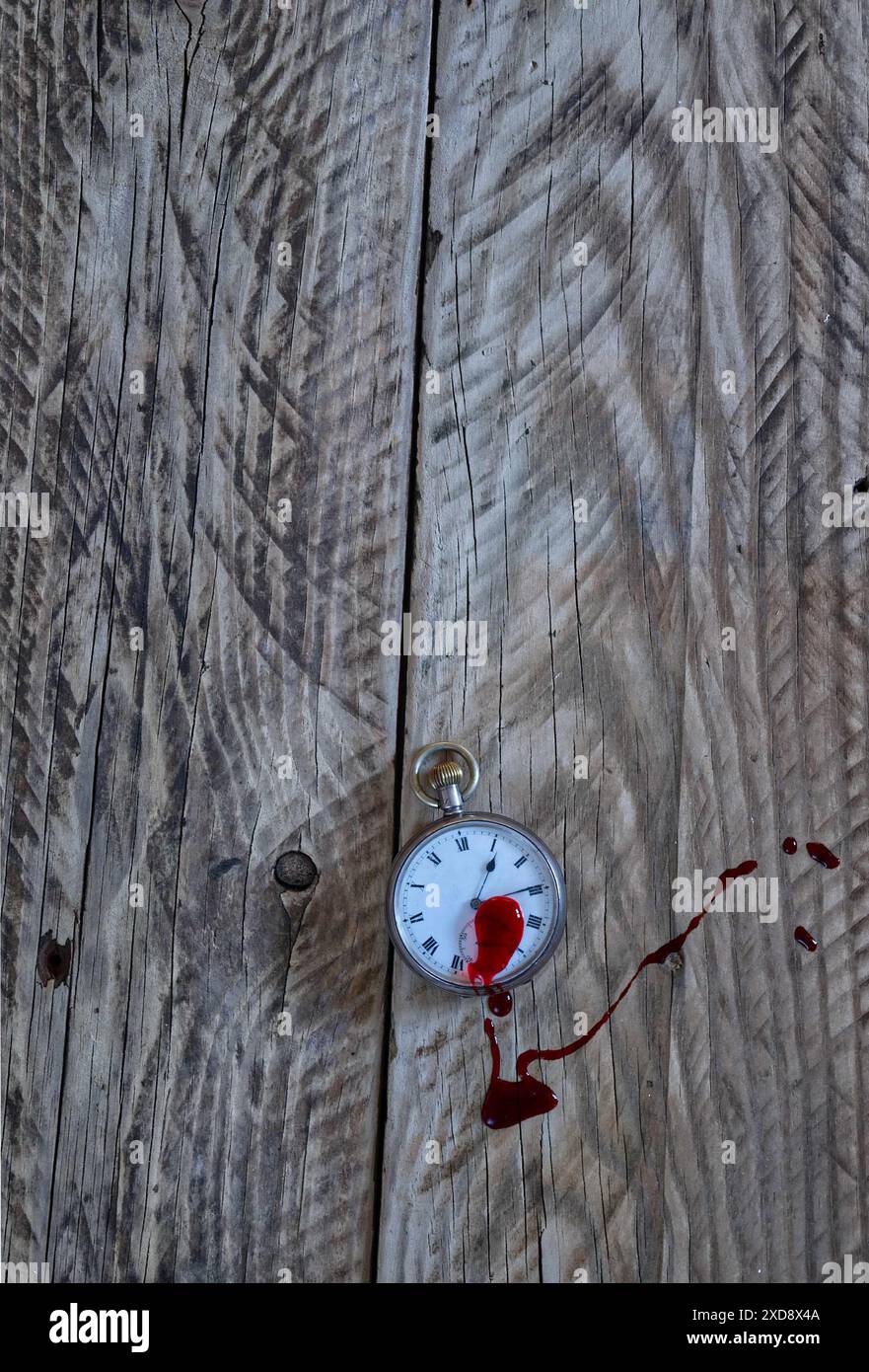An Old pocket watch laying on an old wooden table with blood splatter ...