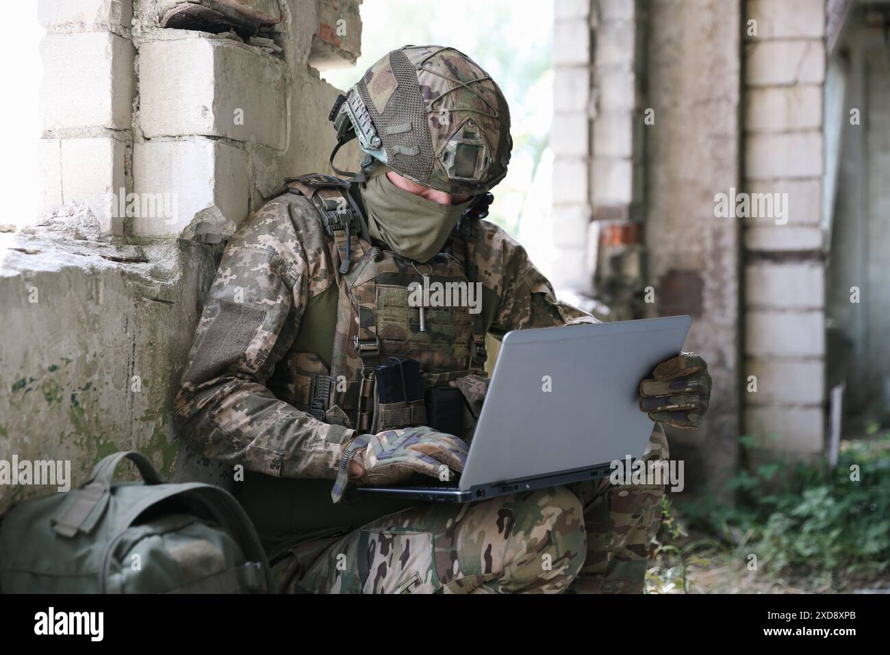 Military mission. Soldier in uniform using laptop inside abandoned ...