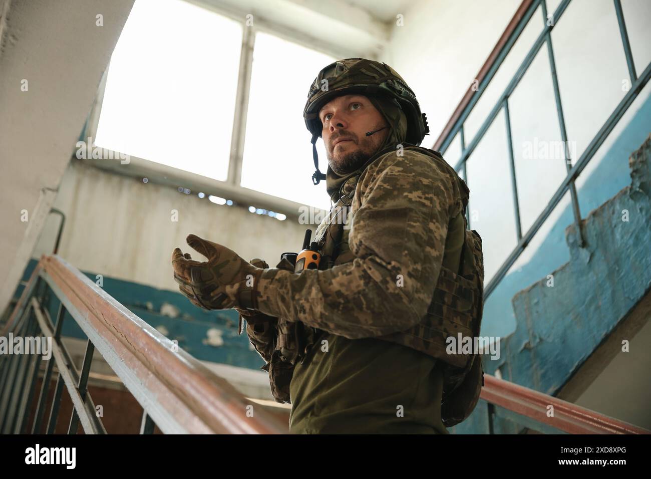 Military mission. Soldier in uniform on stairs inside abandoned ...