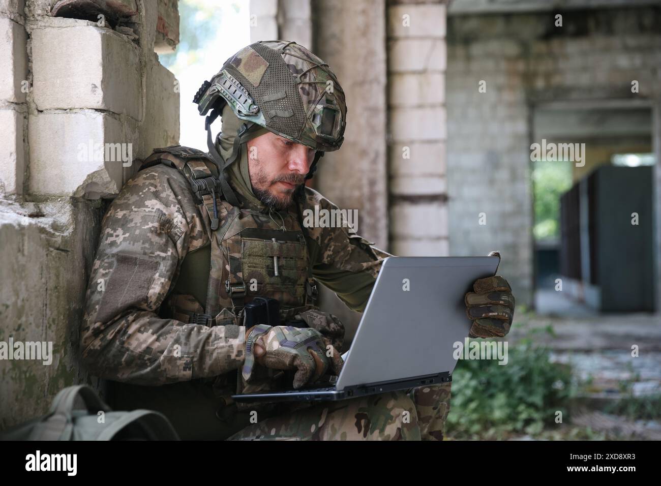 Military mission. Soldier in uniform using laptop inside abandoned ...