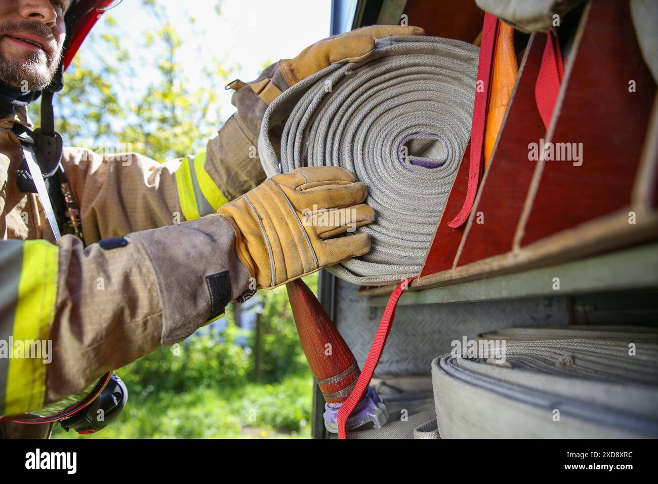 Firefighter in uniform with fire hose near truck outdoors, closeup ...