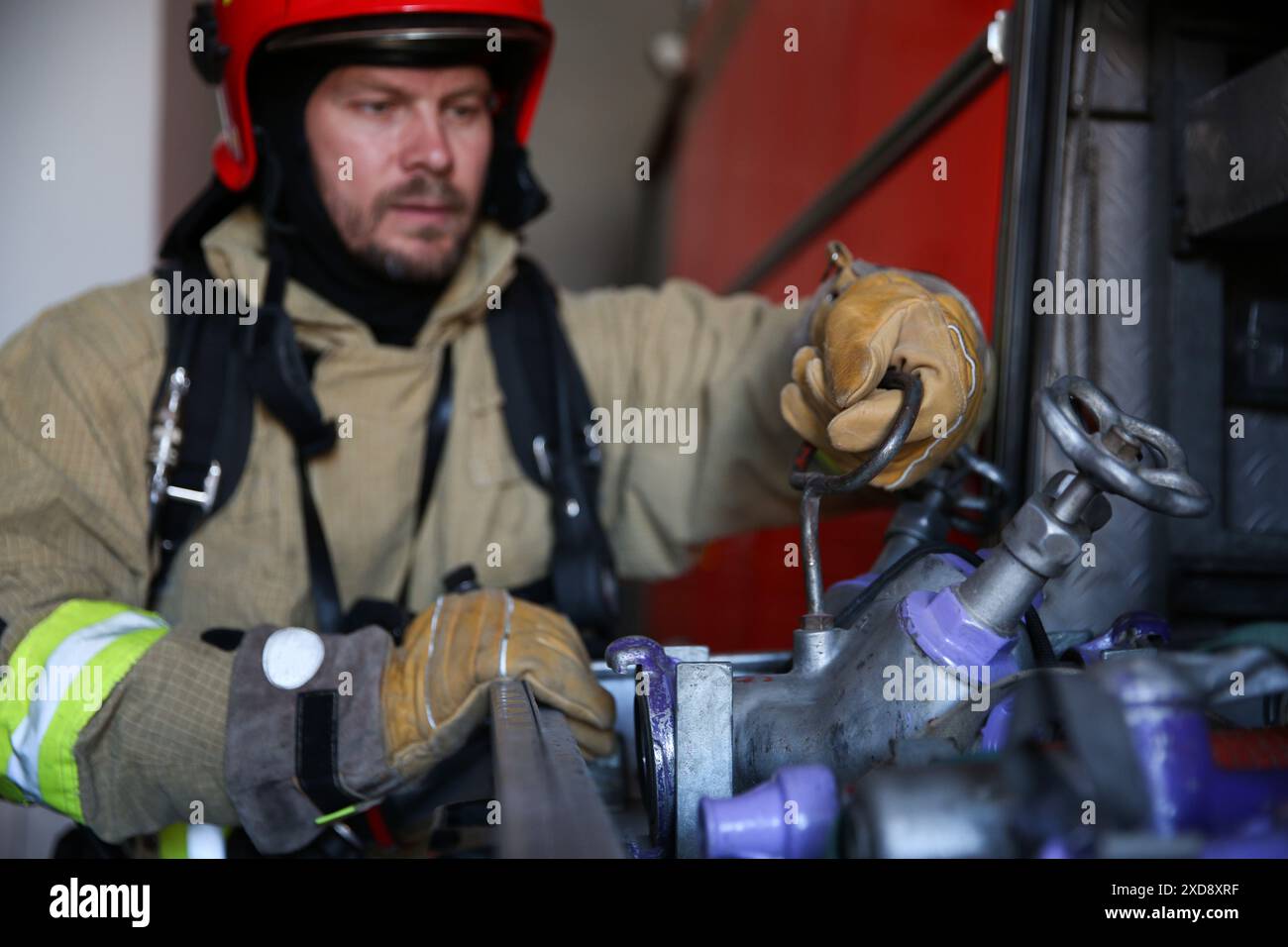 Firefighter in uniform with fire engine equipment at station, selective ...