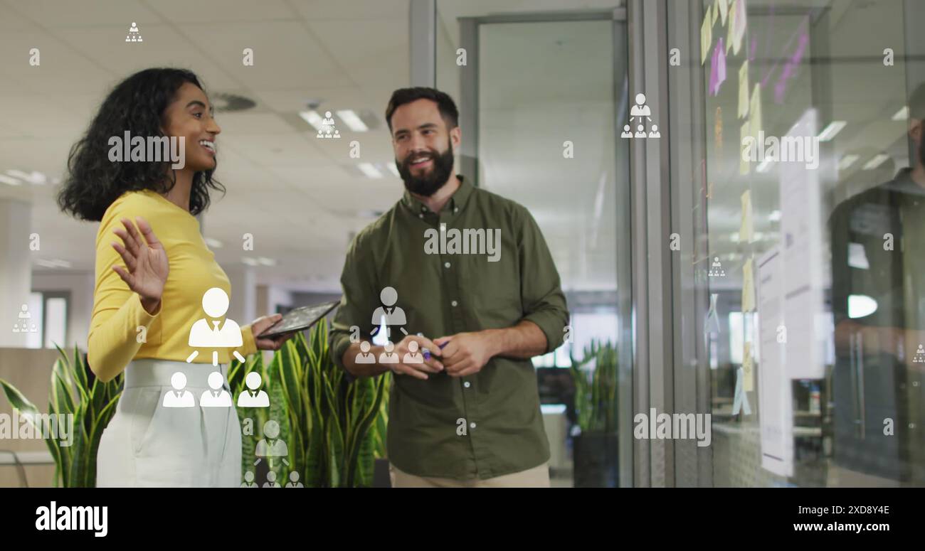 Image of profile icons floating over diverse man and woman discussing ...
