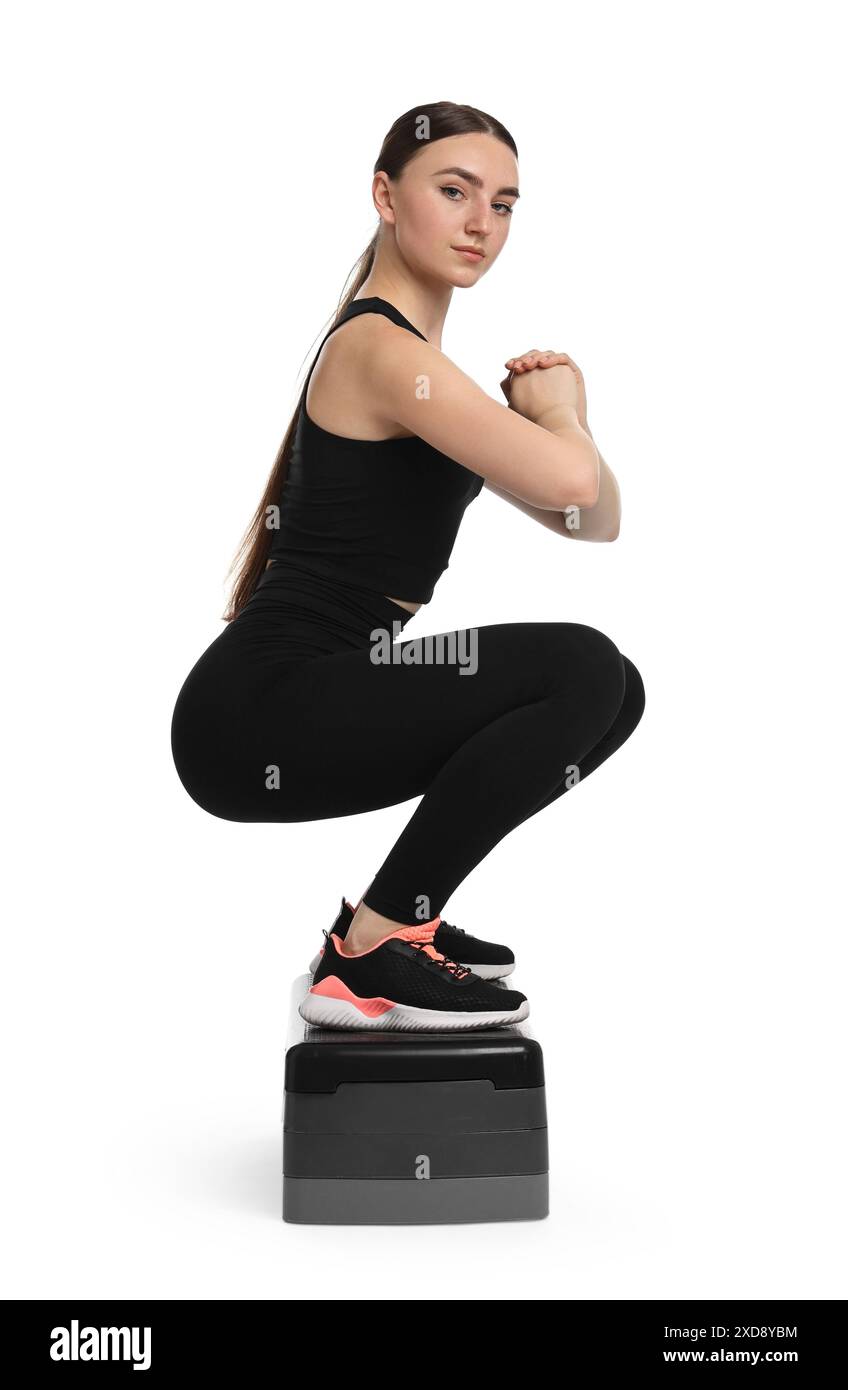 Young woman doing aerobic exercise with step platform on white ...