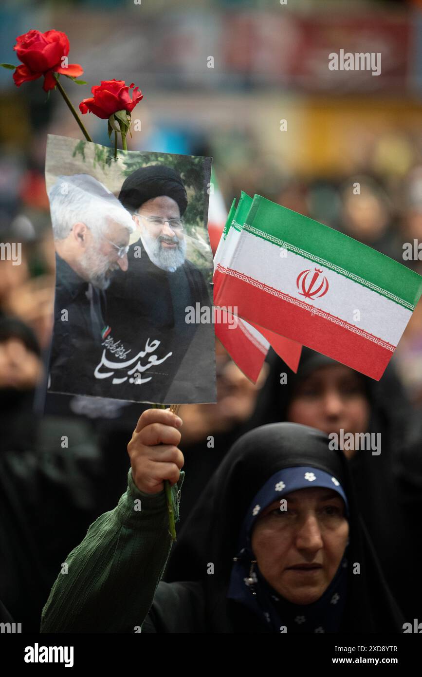 A woman holds up Iranian flags and a poster of Saeed Jalili, the ...