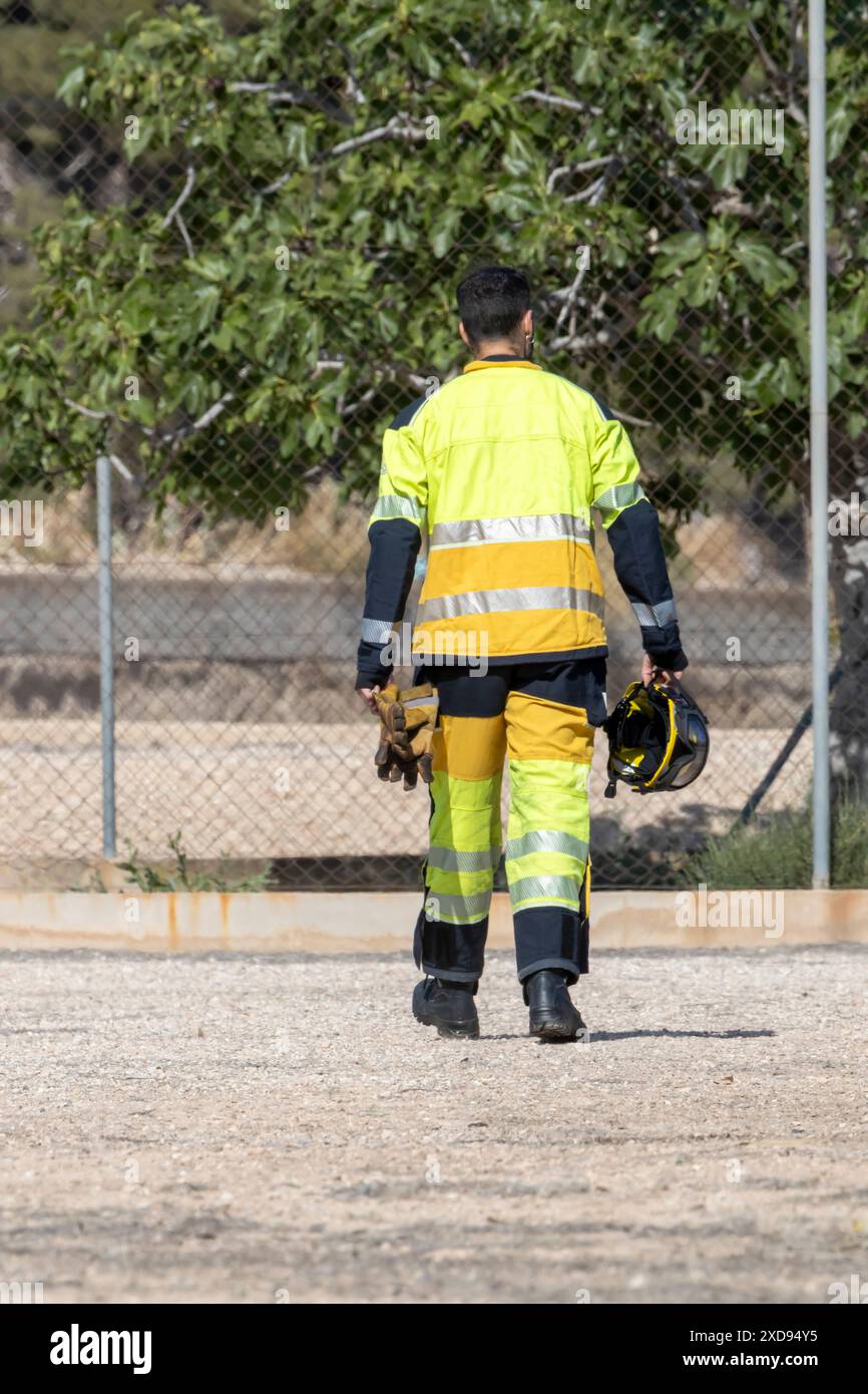 Firefighter with his back turned walking with his uniform and helmet in ...