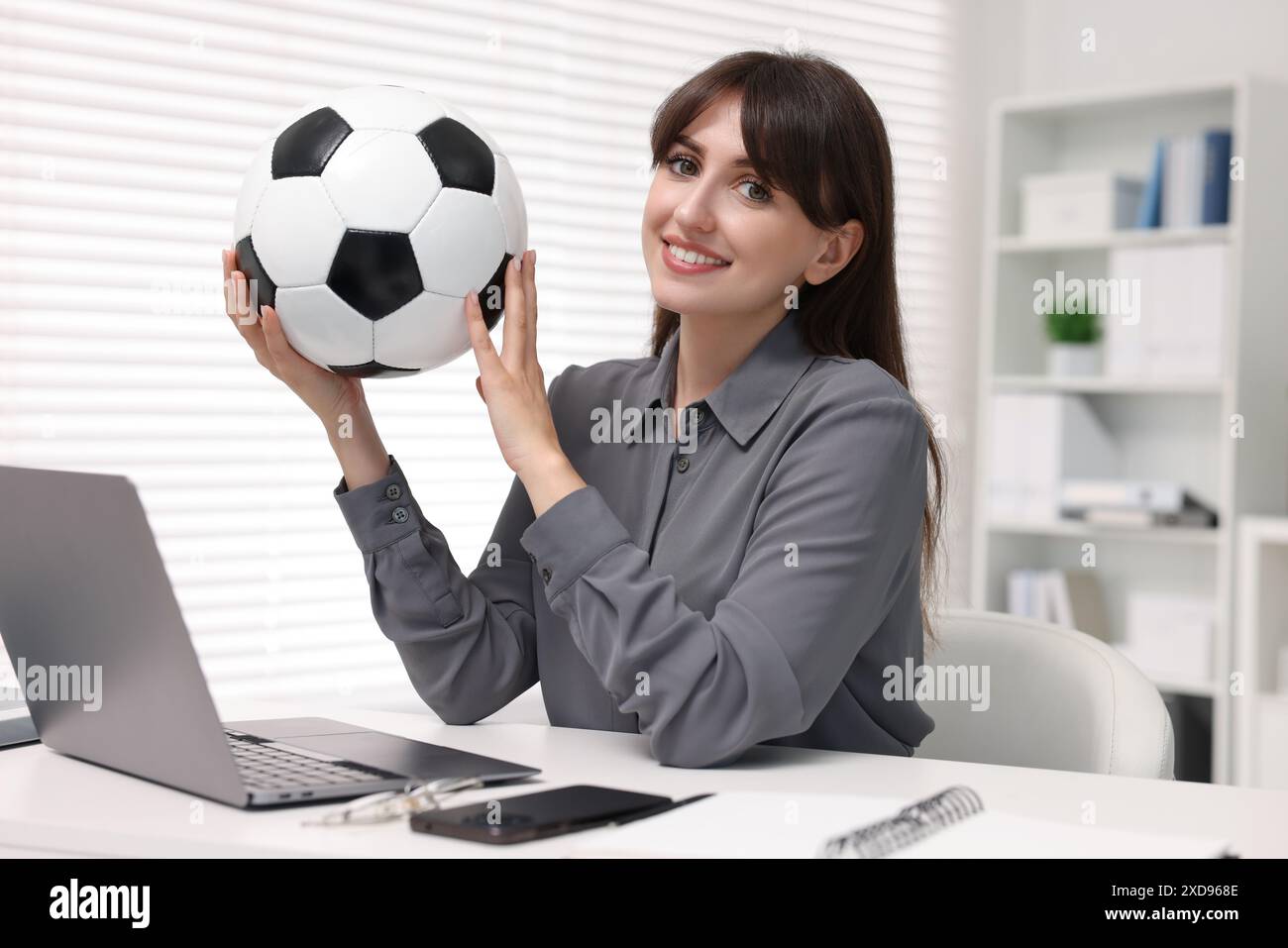 Smiling employee with soccer ball at table in office Stock Photo - Alamy