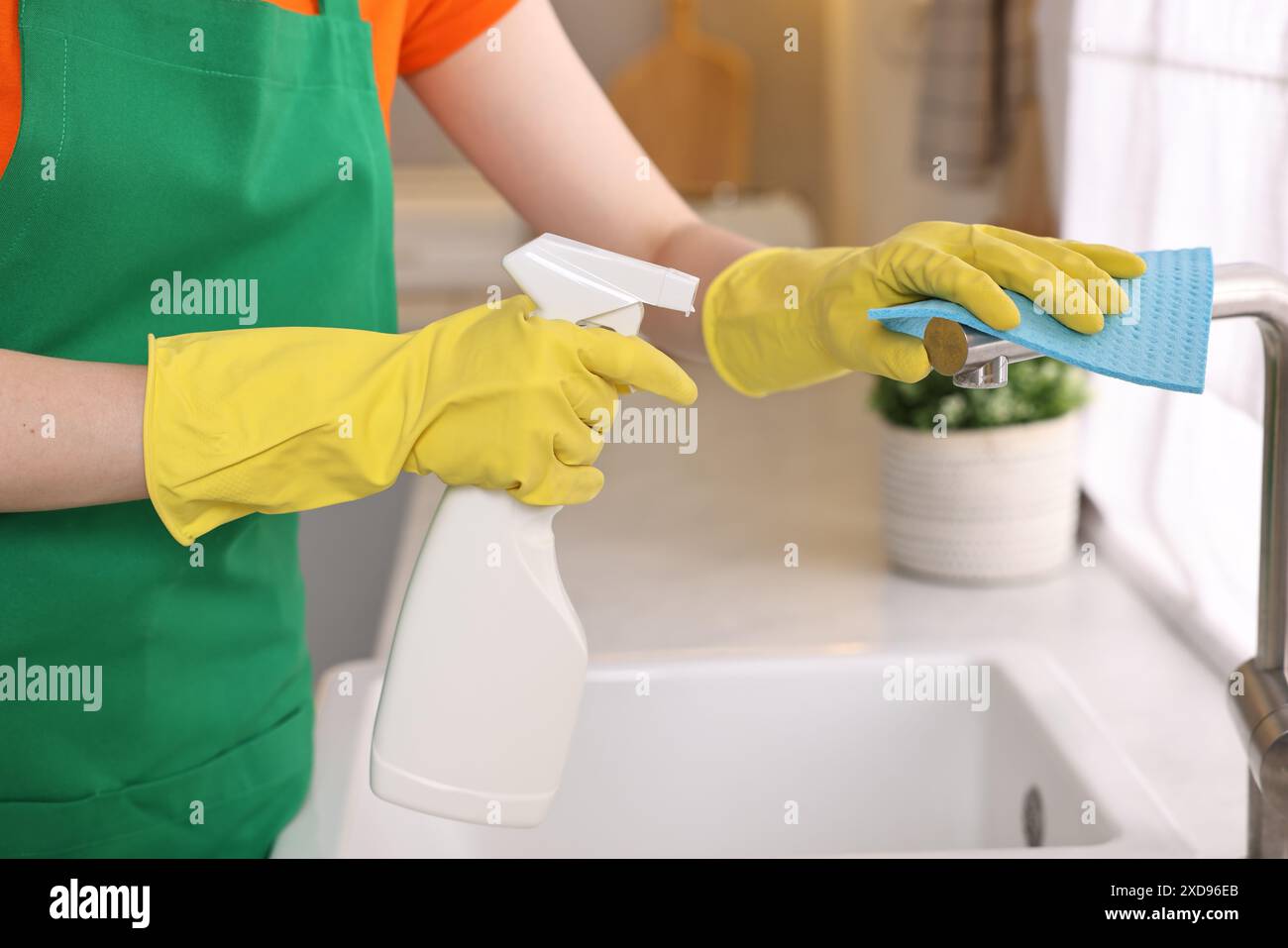 Professional janitor wearing uniform cleaning tap in kitchen, closeup ...