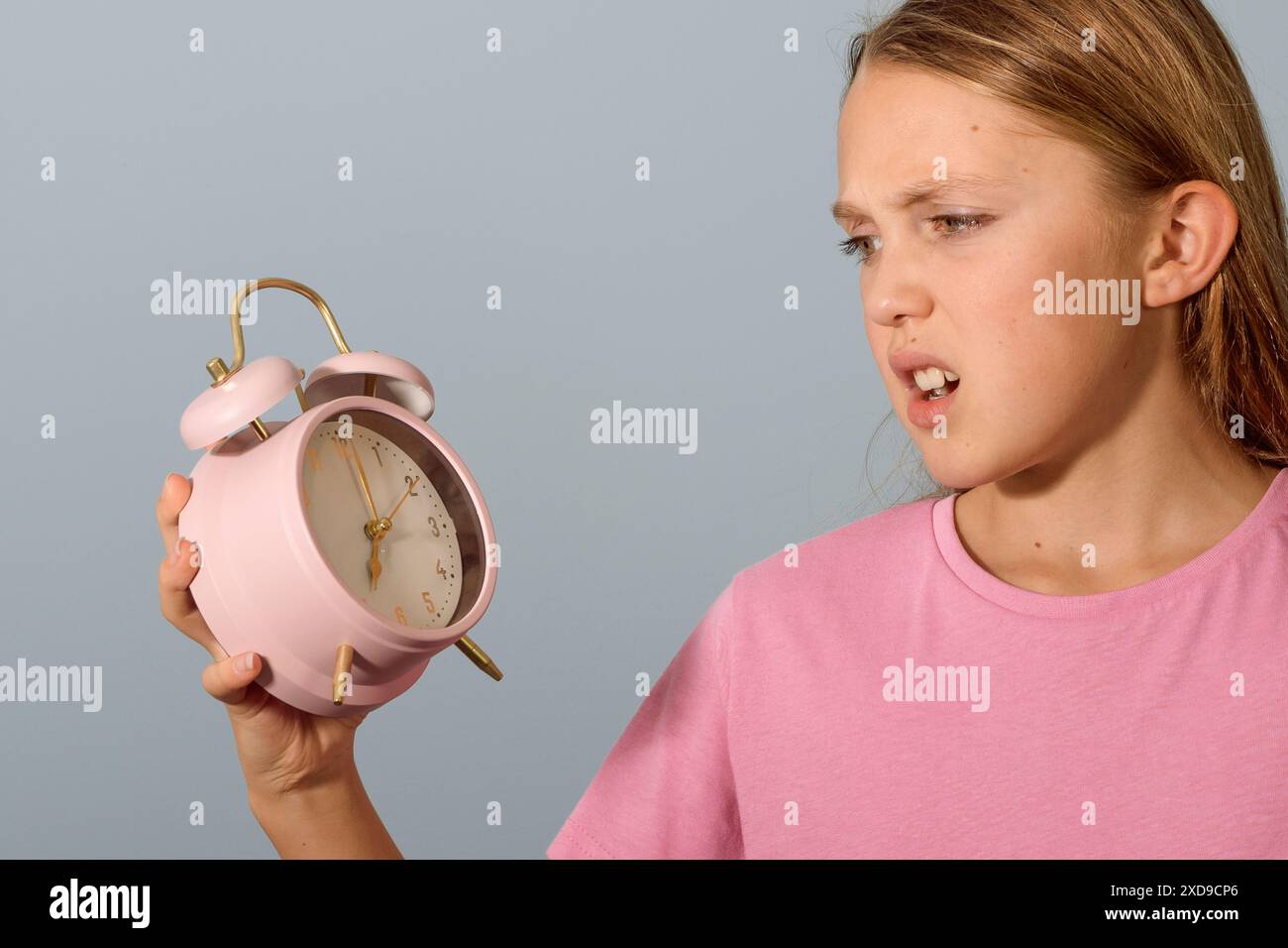 Wake up early. The girl looks at the alarm clock with dissatisfaction ...