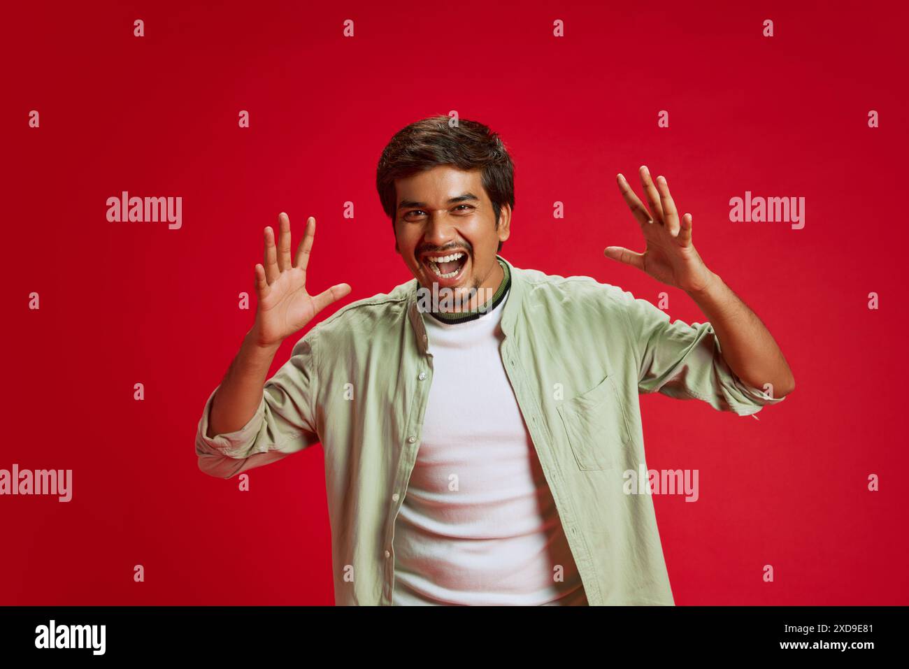Shouting of joy young Indian man raising hand of excitement against red ...