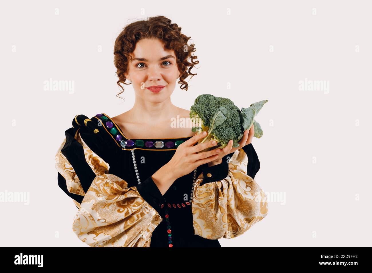 Portrait of a young adult woman dressed in a medieval dress holding a ...