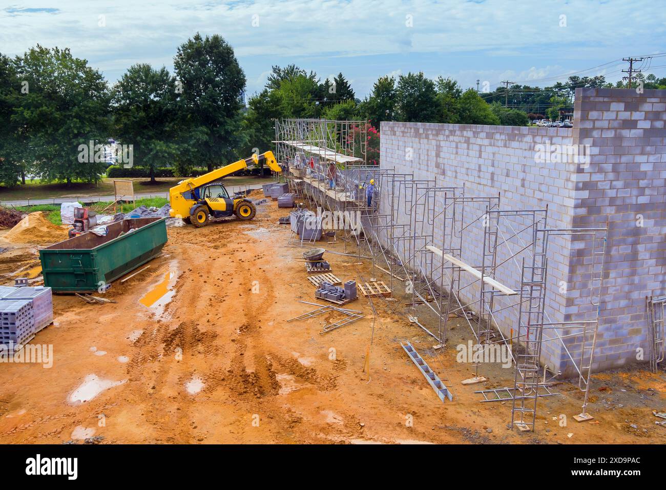Masonry worker standing on scaffolding makes concrete wall using cement ...