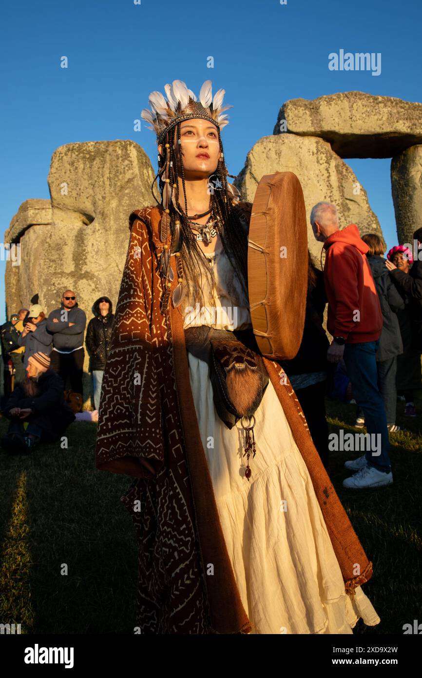 Stonehenge, Wiltshire UK, 21st June 2024. A women wearing traditional Native American dress ...