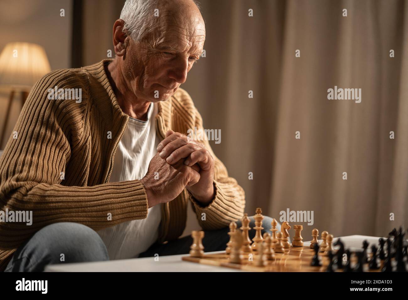 Thoughtful elderly man playing Chess on chess-board game at home for ...