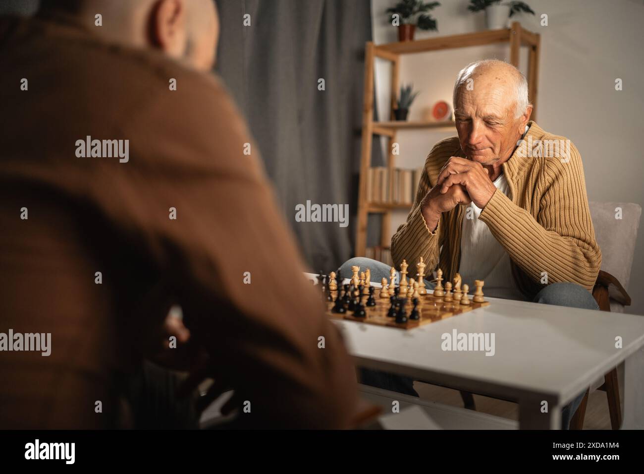 Elderly man playing chess with younger opponent Stock Photo - Alamy