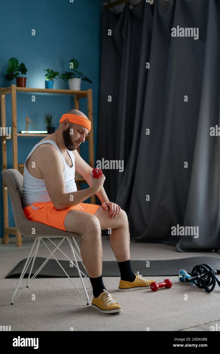 Funny man with an orange bandage on his forehead lifts dumbbells and ...