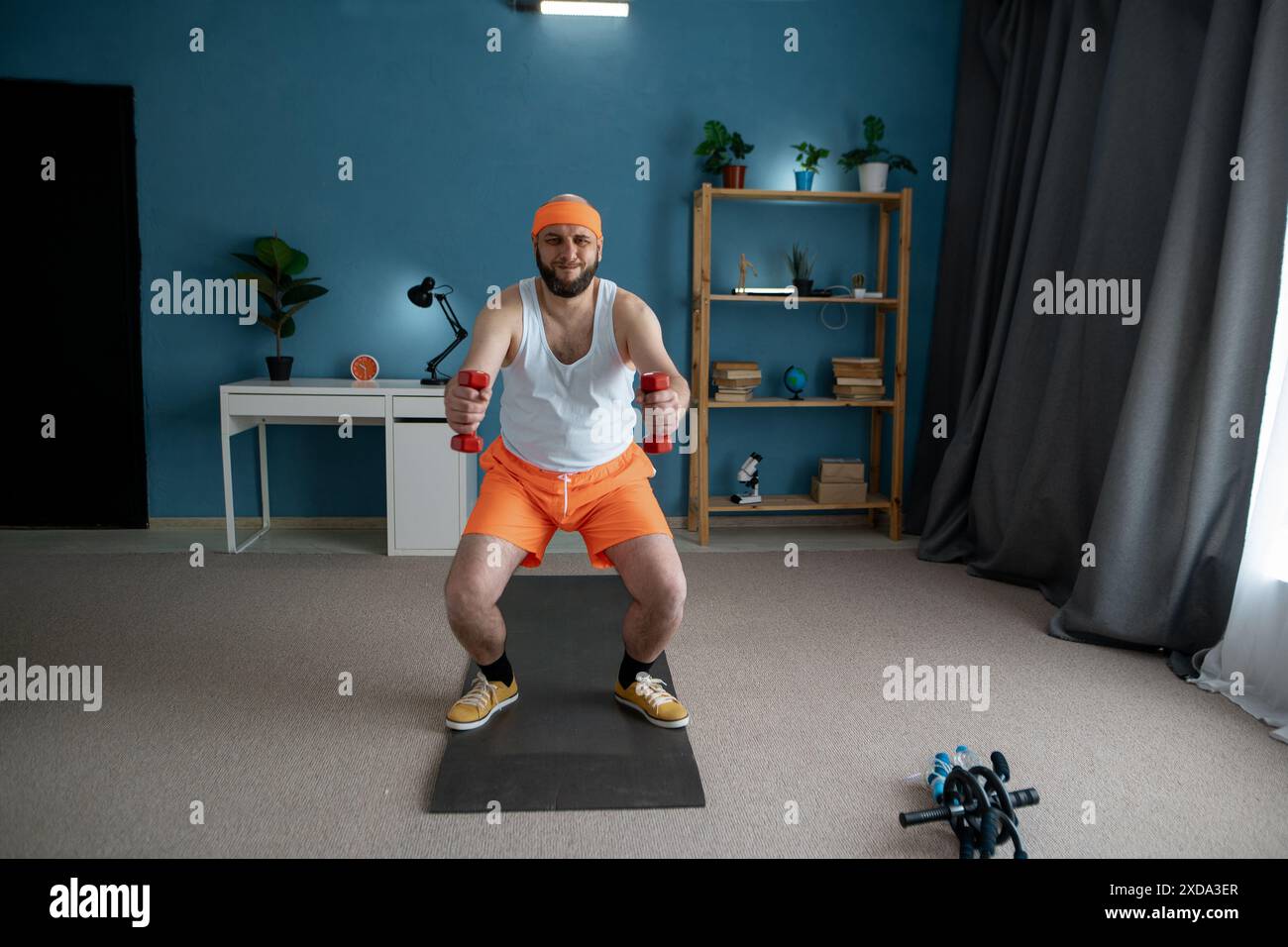 Funny man performs sports exercises at home using dumbbells. Male ...