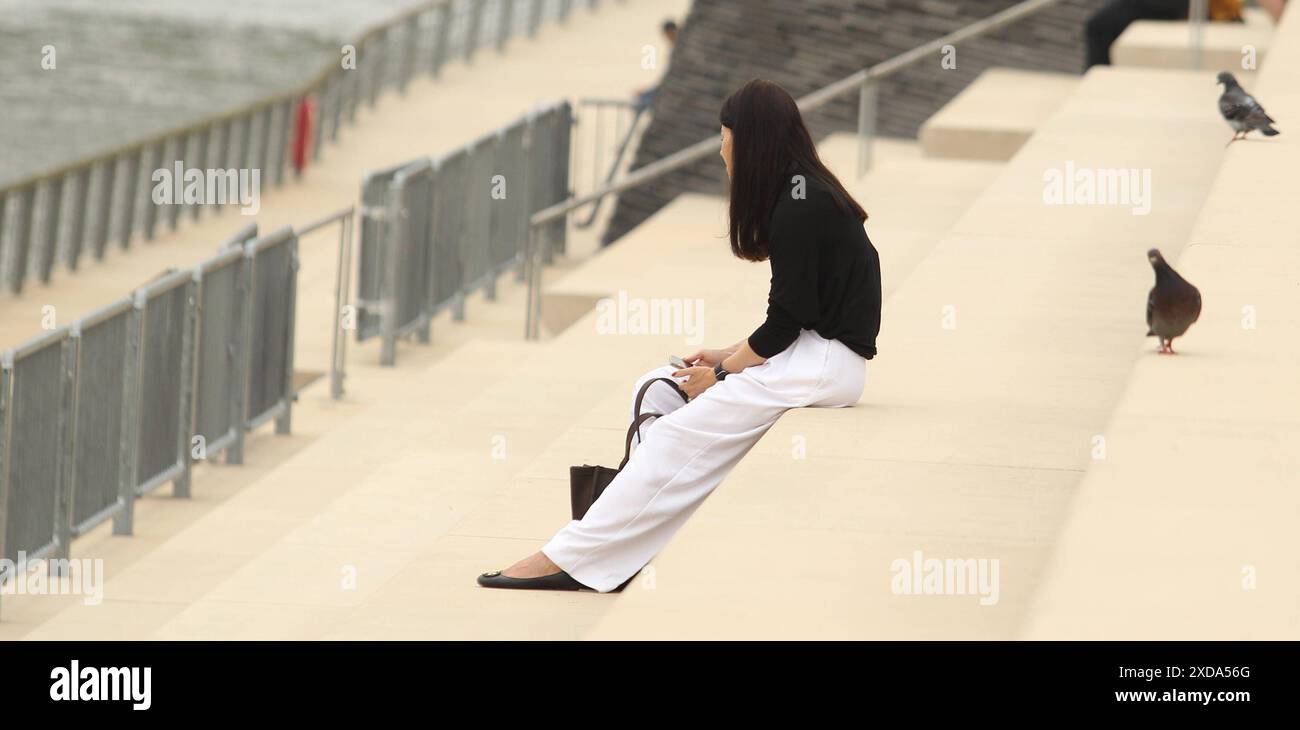Eine Frau sitzt ganz allein auf einer Treppe am Rheinufer. Symbolbild ...