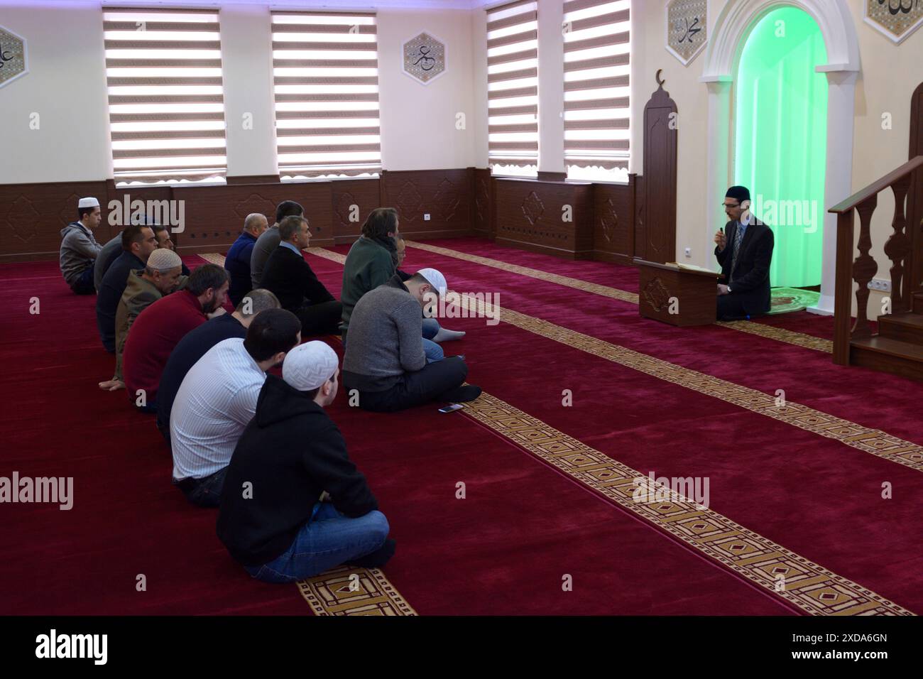 Group of Muslim men sitting on a floor and listening to mullah ...