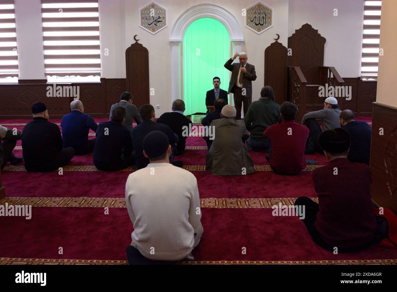 Group of Muslim men sitting on a floor and listening to mullah ...