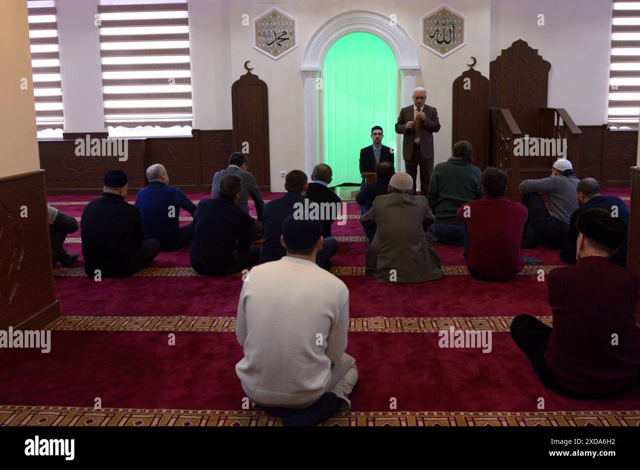 Group of Muslim men sitting on a floor and listening to mullah ...