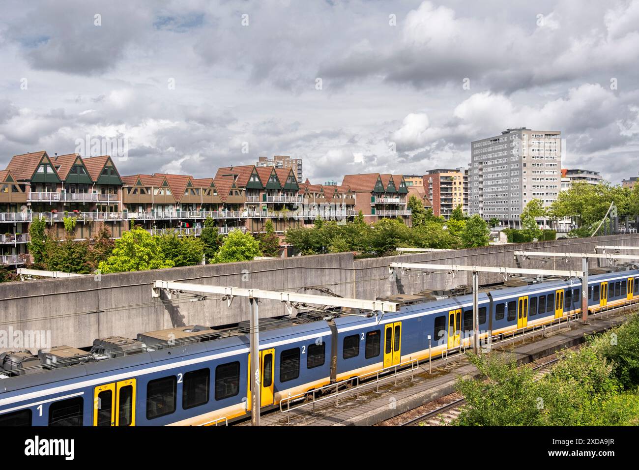 Train moving past residential buildings and greenery in an urban area ...