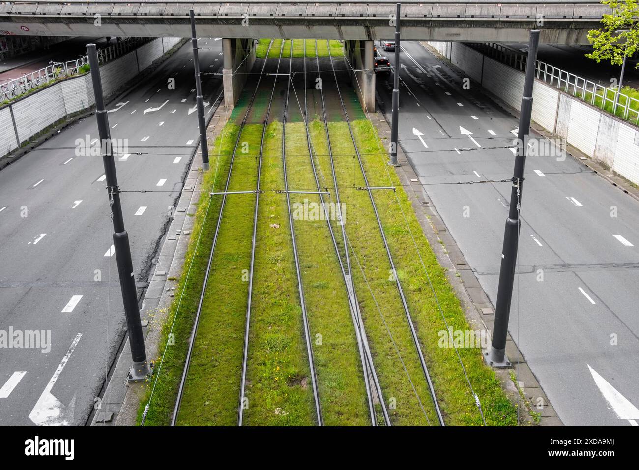 Railway tracks with green grass underneath passing under a bridge, with ...