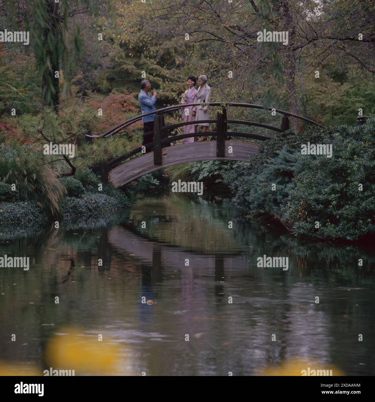 Husband taking picture of wife and Japanese girl on bridge Stock Photo ...