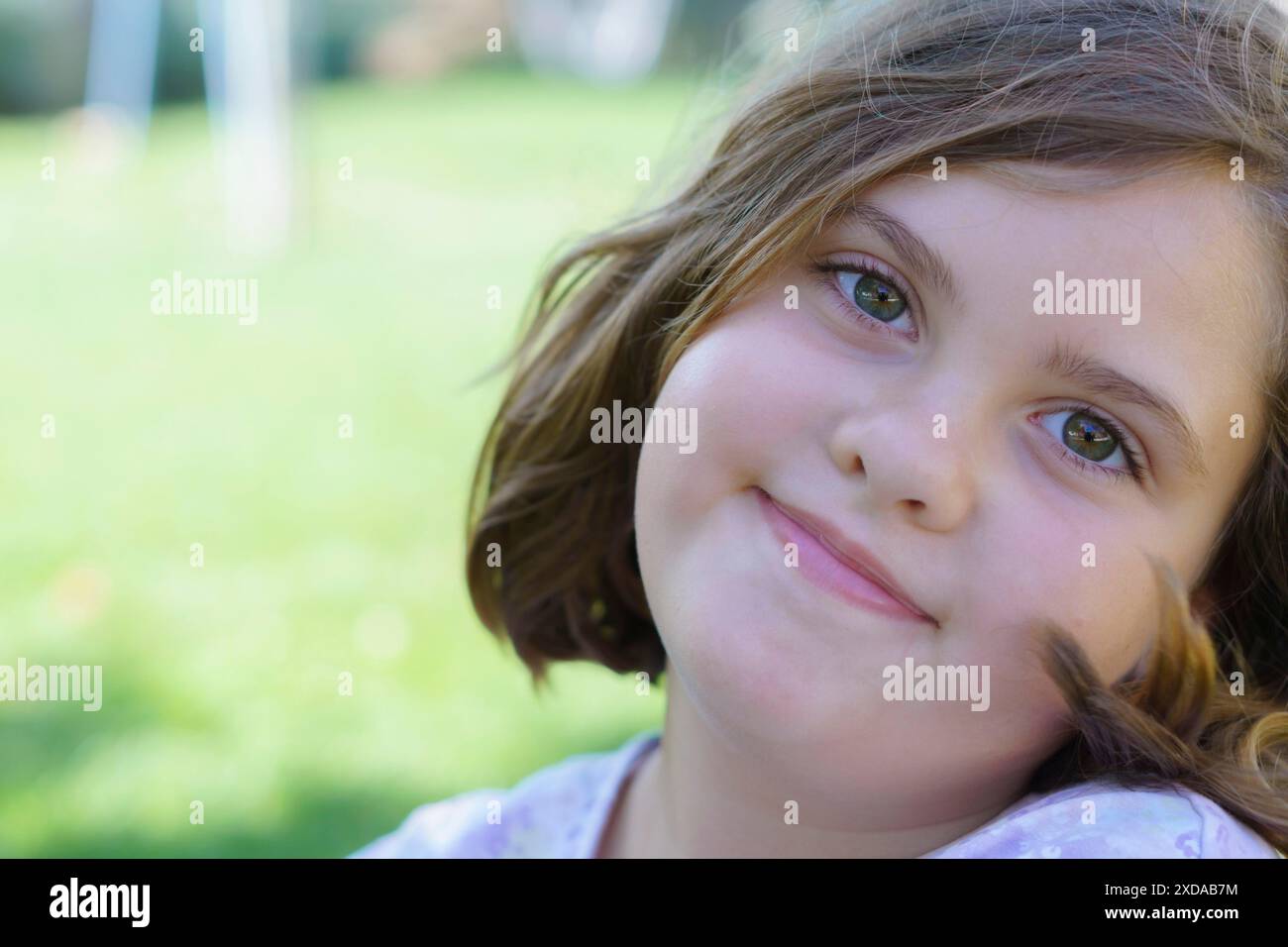Portrait of a beautiful little blonde girl in a colorful dress smiling ...