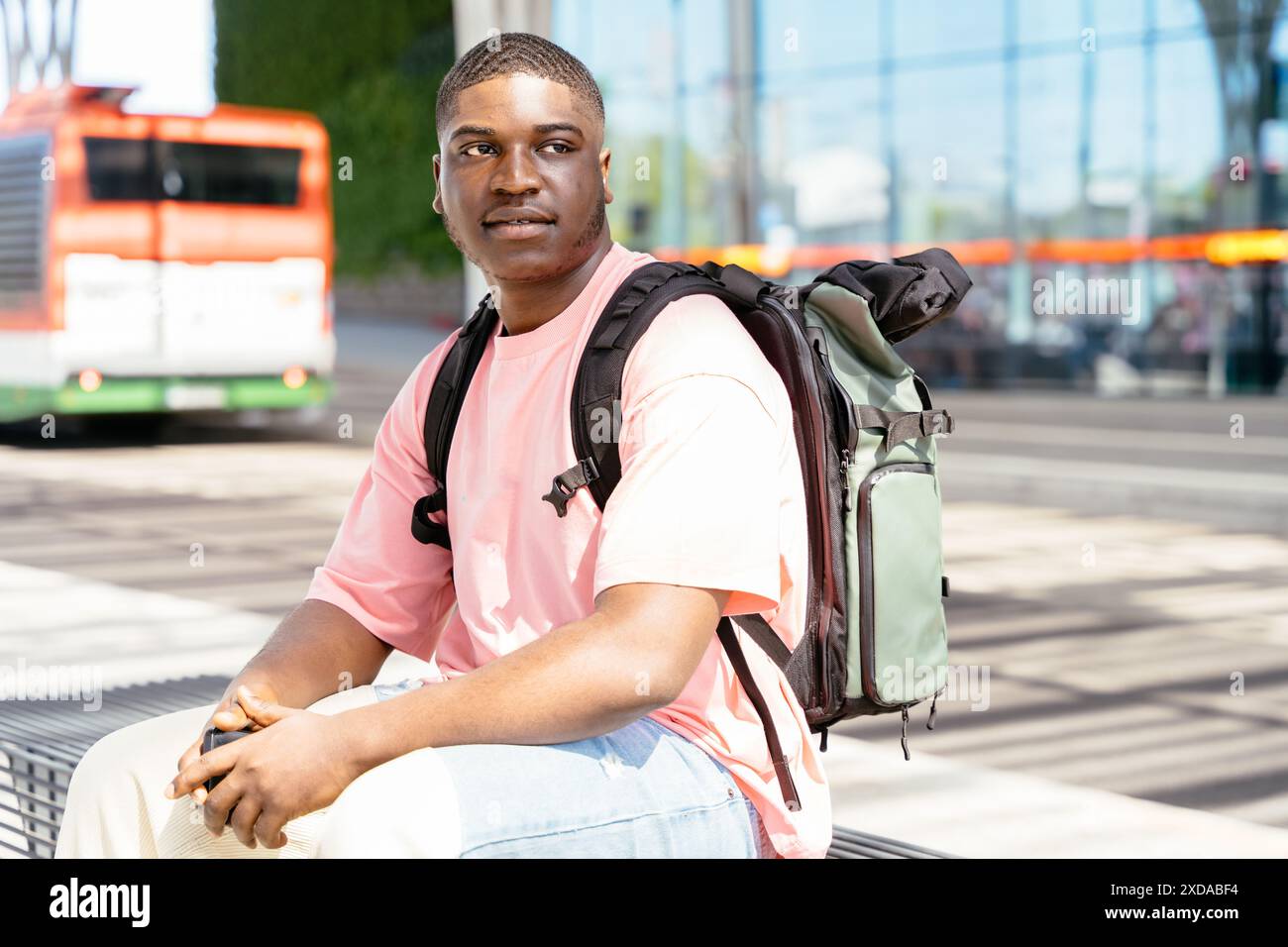 African student man traveler sits on a bench waiting for bus outdoor ...