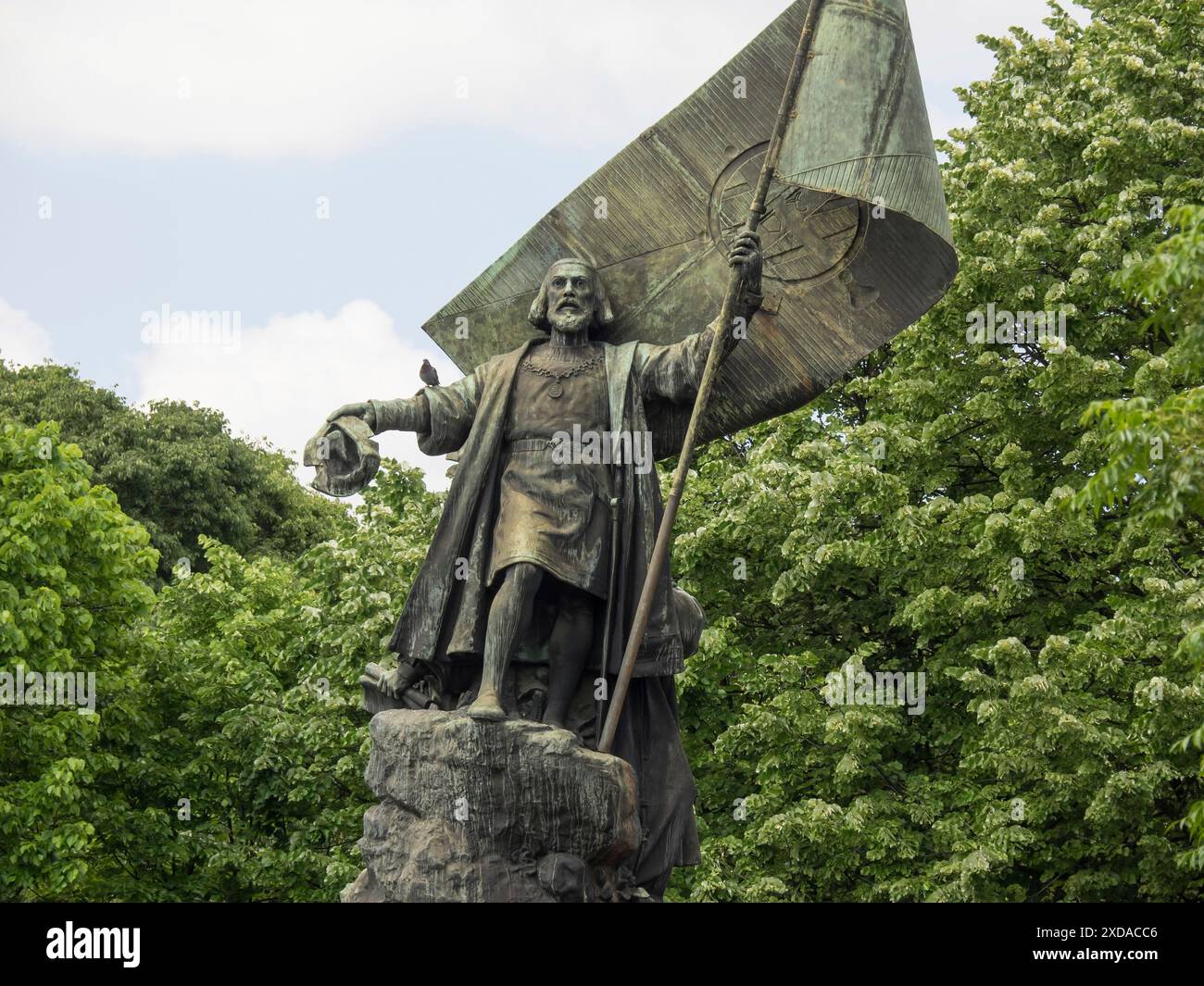 Statue of a historical figure with flag in the background of trees and ...
