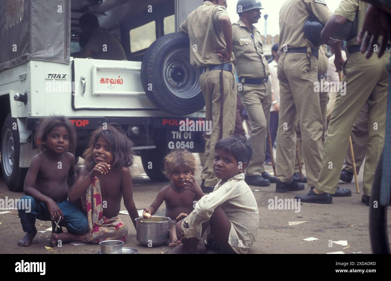 poor children with some food in front of a group of police men on a ...