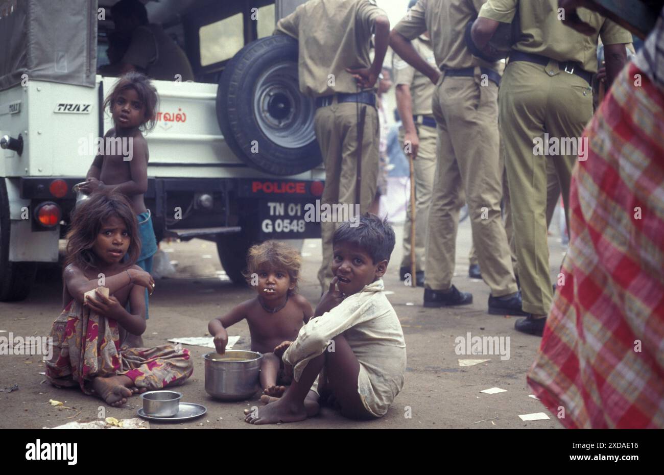poor children with some food in front of a group of police men on a ...