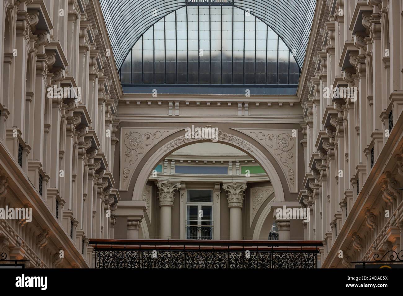 Dark historic interior with glass roof and ornate arches and columns ...