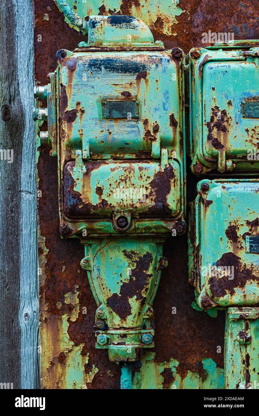 A close-up image showcasing three rusty green electrical boxes mounted ...