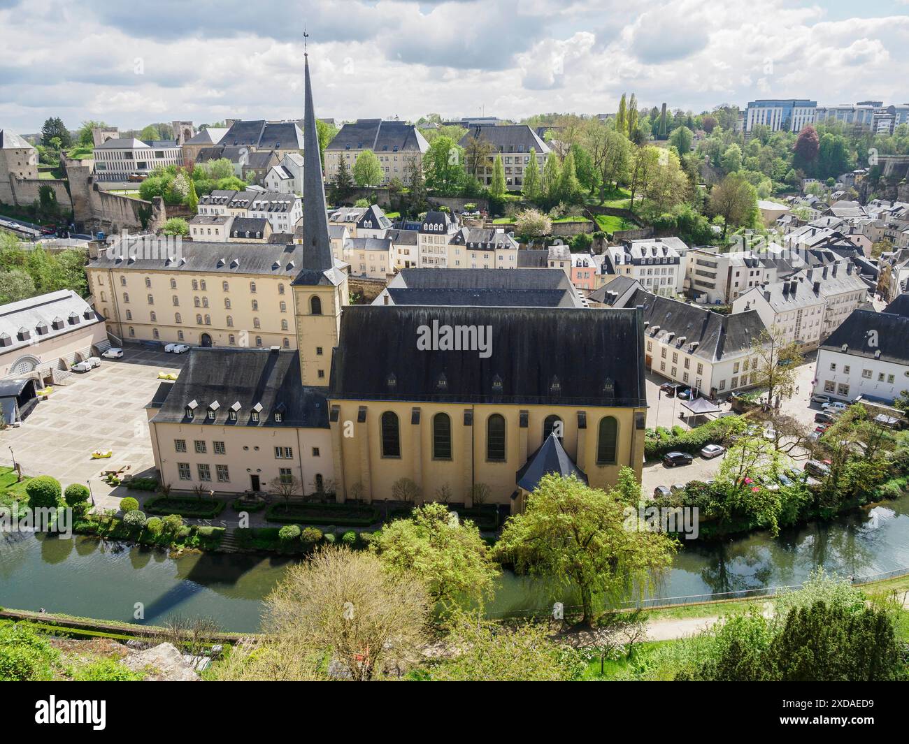 Historic church by the river, surrounded by green trees and urban ...