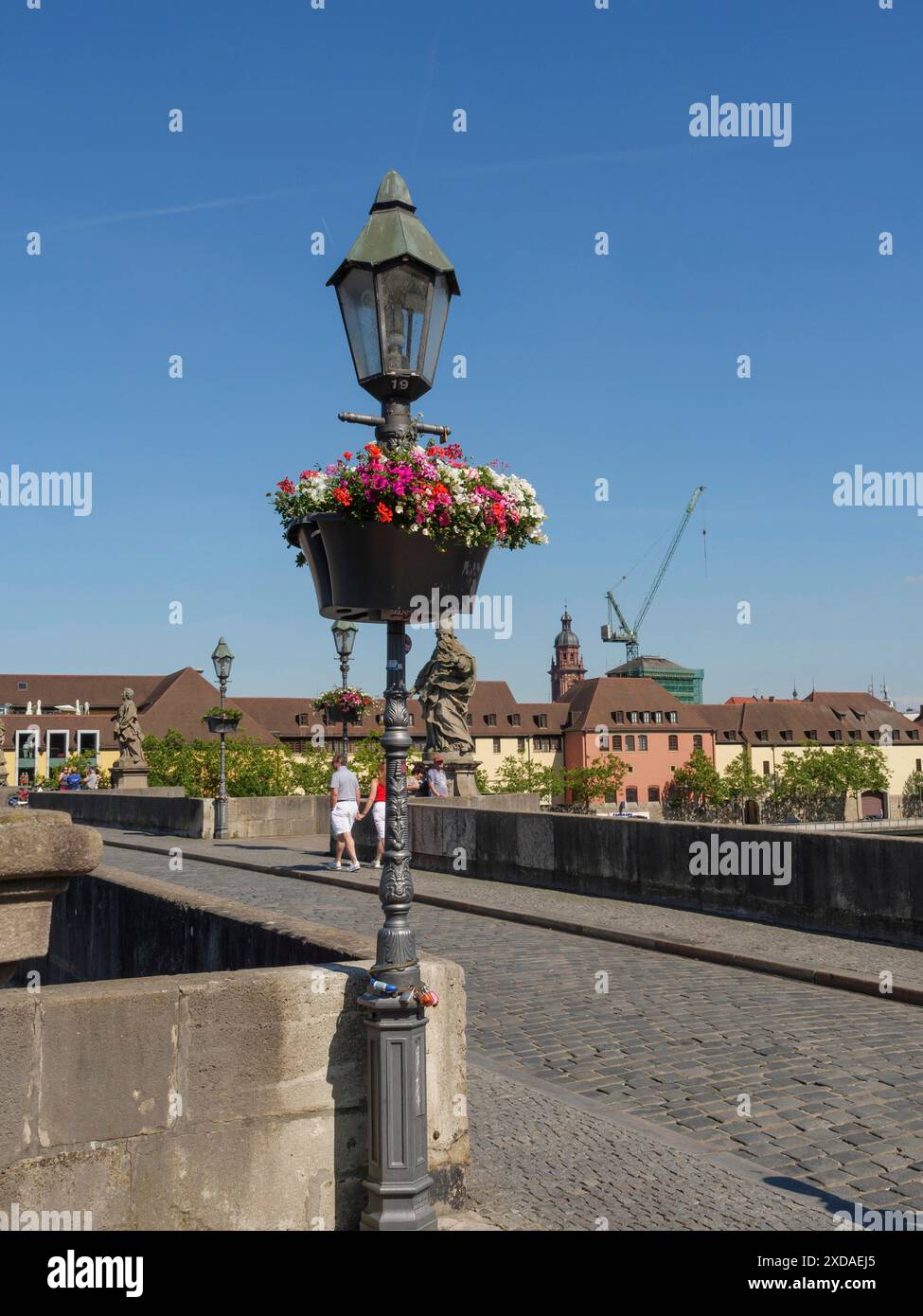 Lantern with flower basket on a bridge, lined with historic buildings ...