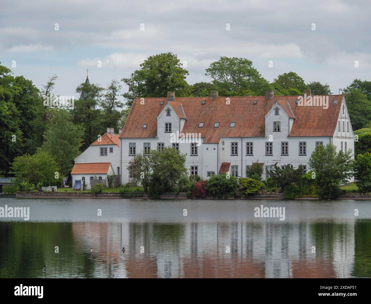 A large white manor house with red roofs reflected in a neighbouring ...
