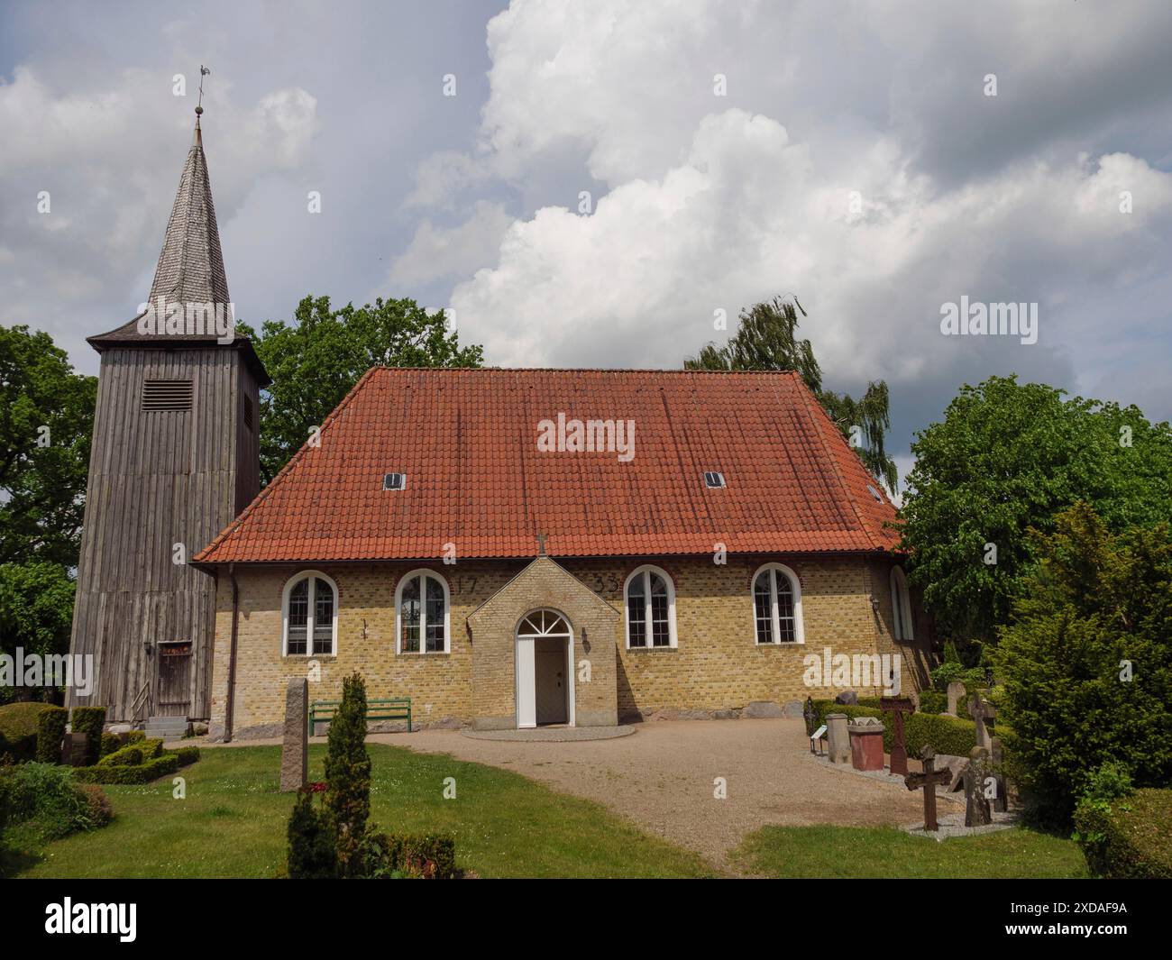 Small church building with red tiled roof and wooden tower in front of ...