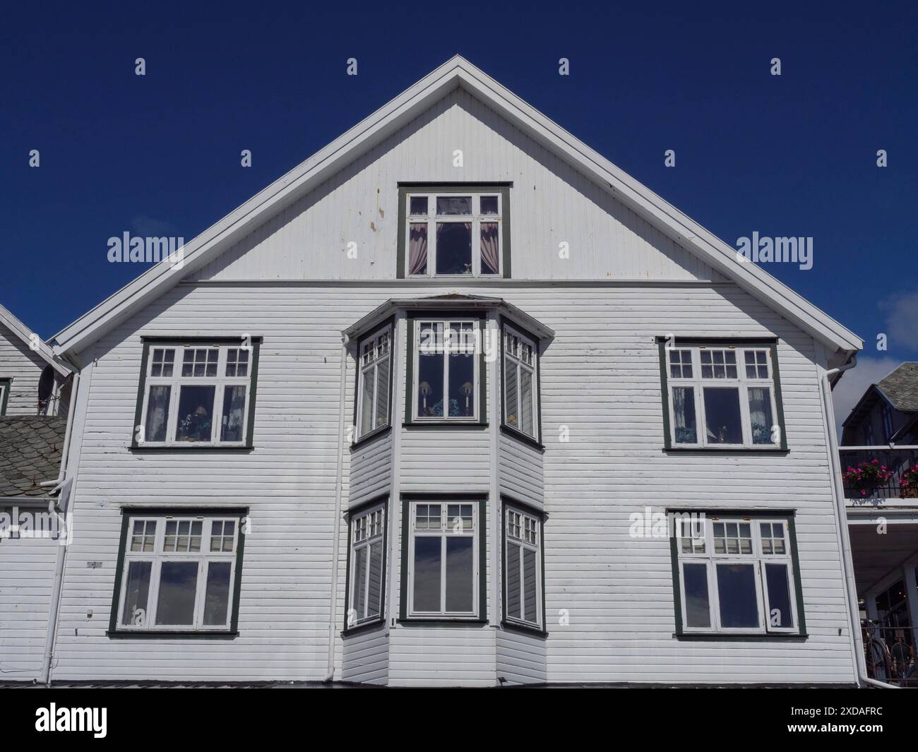 White house with wooden facade and many windows under a blue sky ...