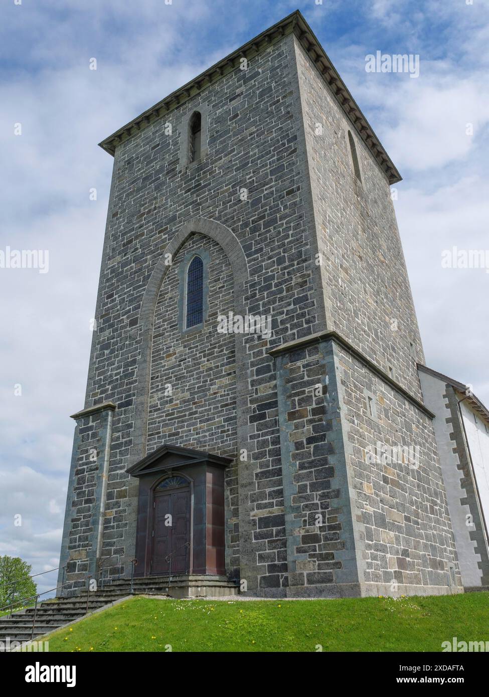 Massive stone church tower with architectural details under a cloudy ...