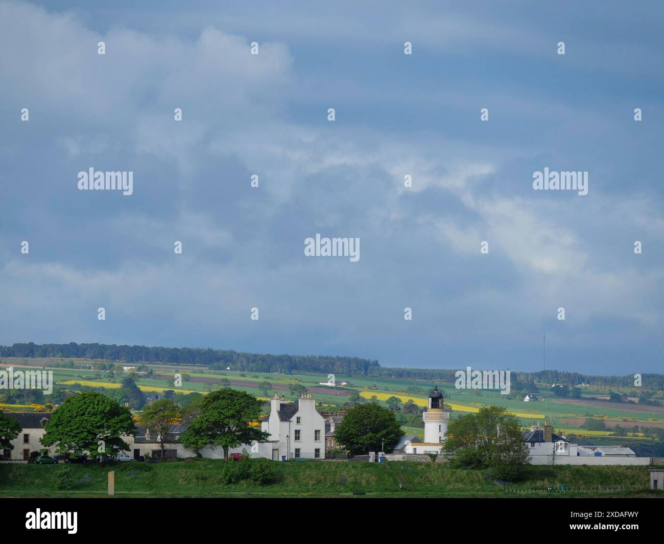 A village with white buildings and a tower in front of a wide landscape ...