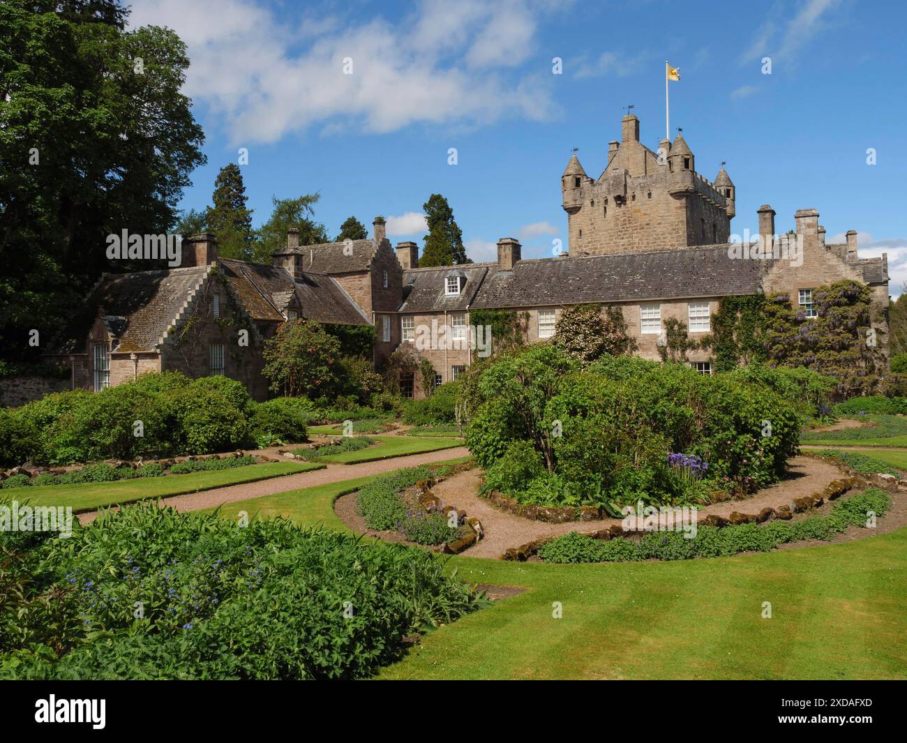 Historic castle with manicured garden, hedges and flowers under a blue ...
