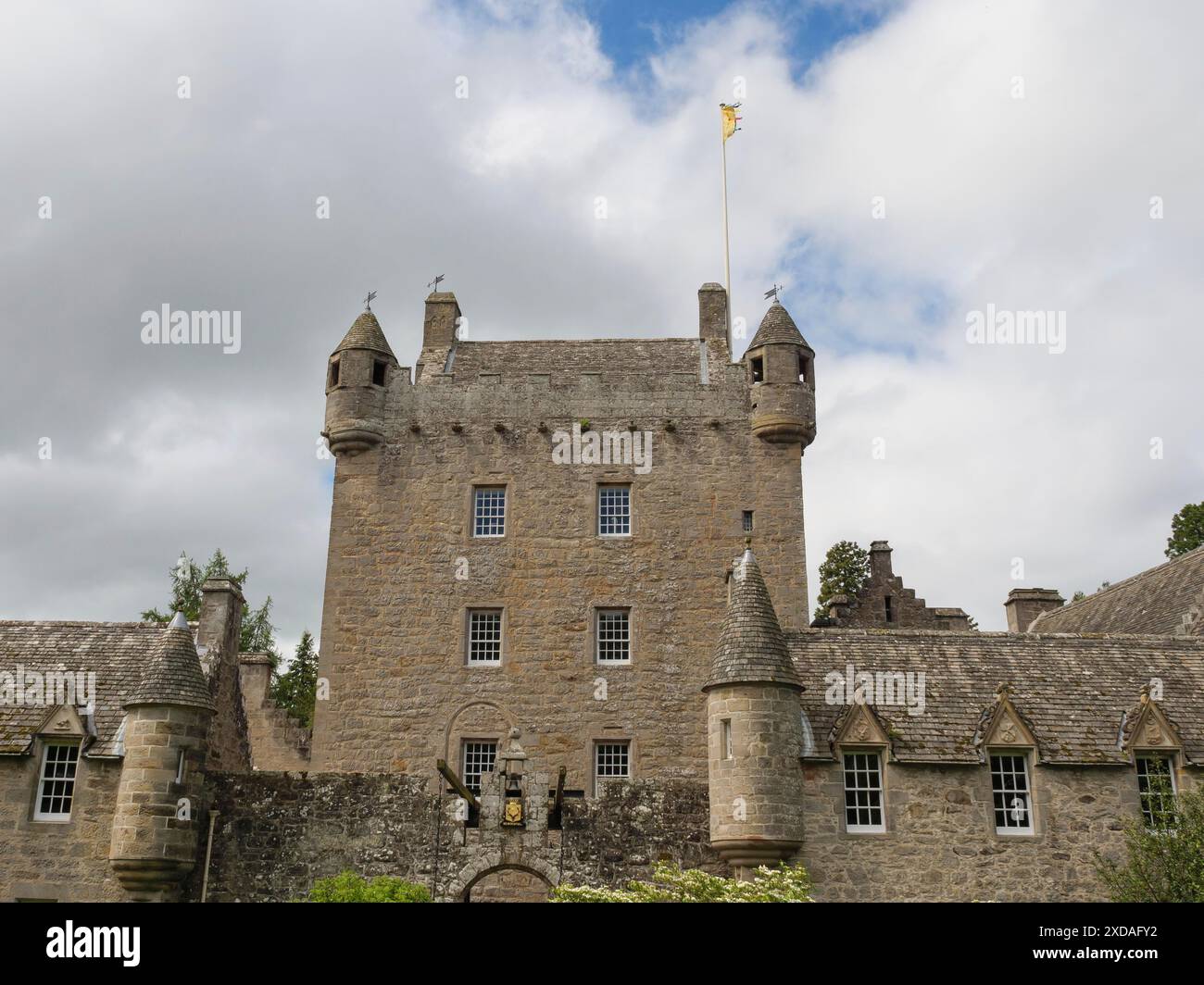 Old castle with stone towers and waving flag under a cloudy sky ...