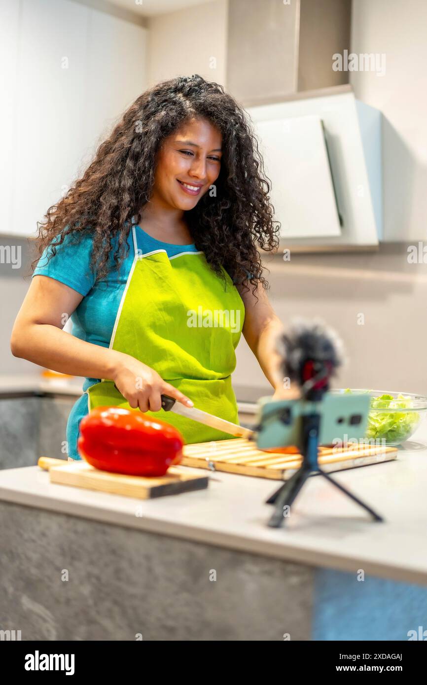 Vertical photo of a latin young female pretty live streamer cooking ...